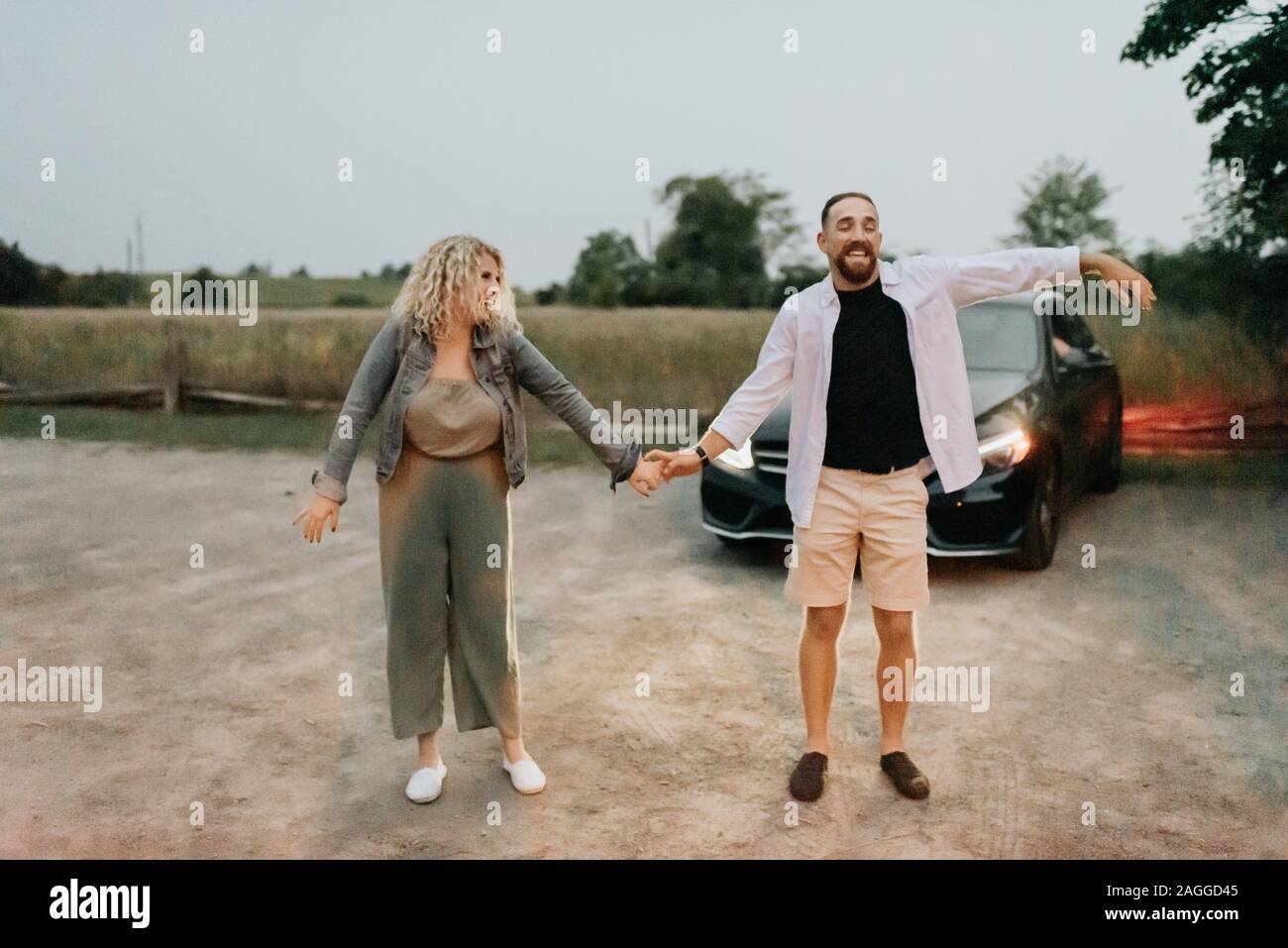 Young couple doing arm wave move in countryside, holding hands Stock ...