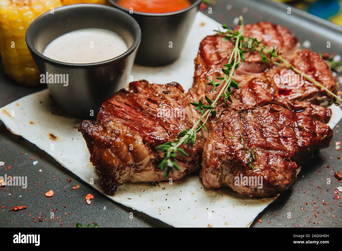 A juicy grilled meat steak with two sauces sits on a black square plate ...