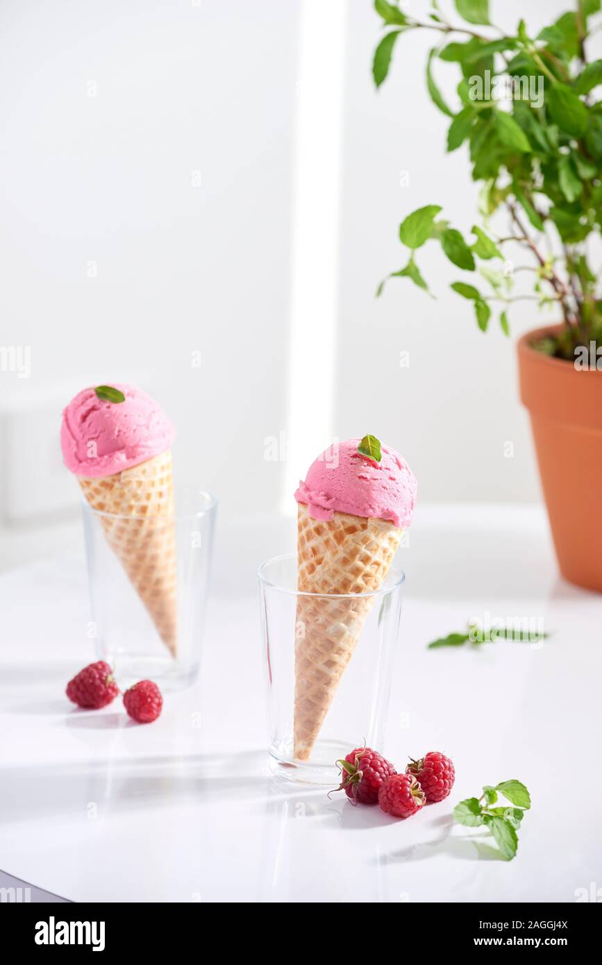 Waffle cone filled with fresh raspberry ice cream in glass cup with ...