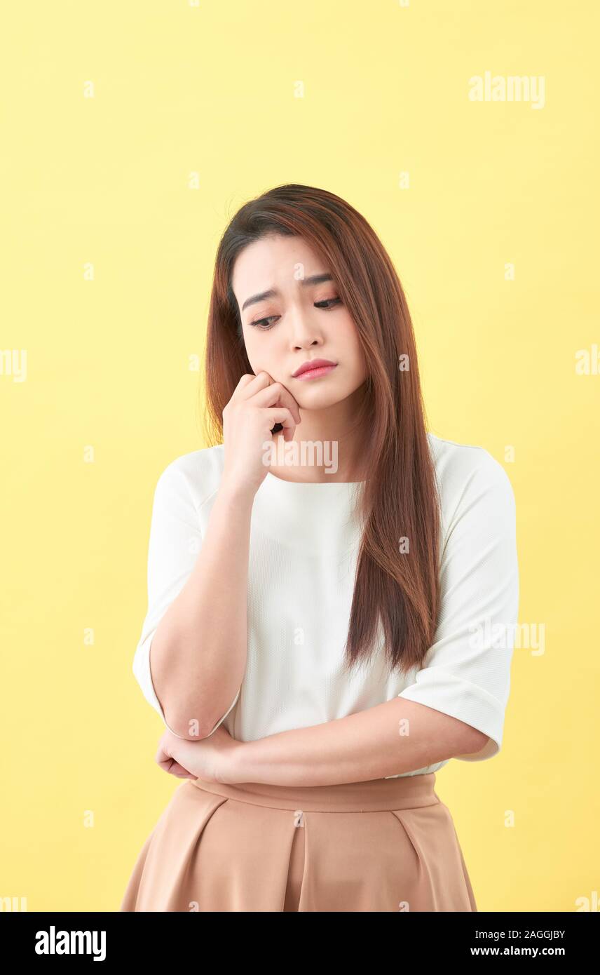 confused young girl thinking on yellow background Stock Photo - Alamy