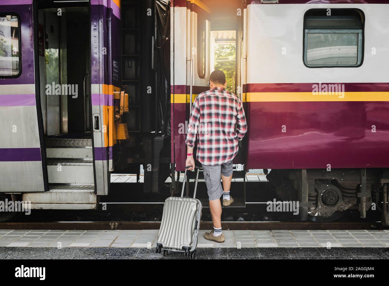 Traveler with baggage is stepping up the train in train station ...