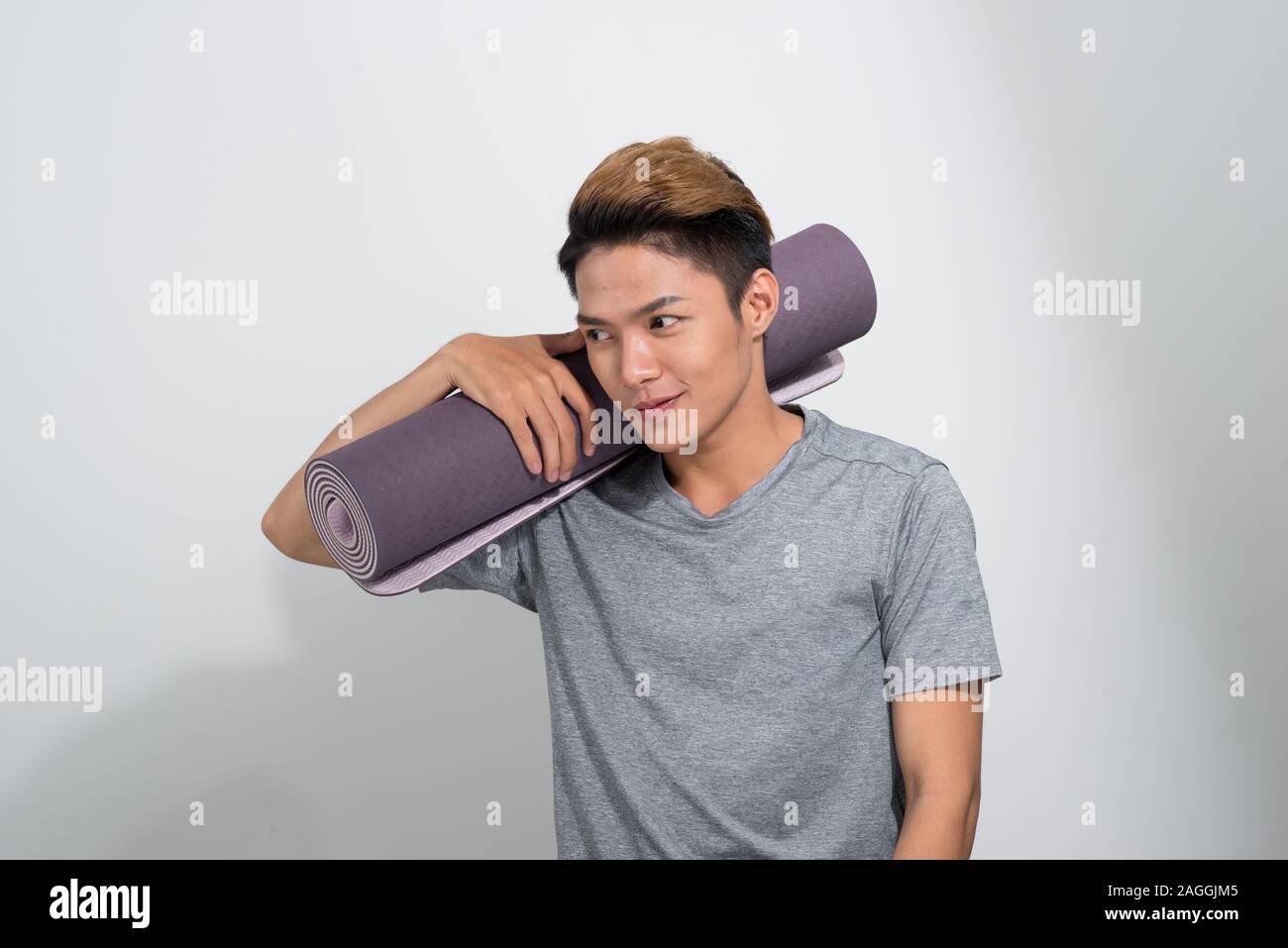 Fitness man holding rolled up exercise mat Stock Photo - Alamy