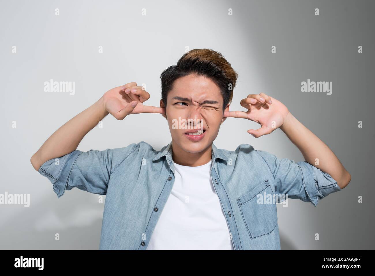 Annoyed young emotional man plugging ears with hands, isolated white ...