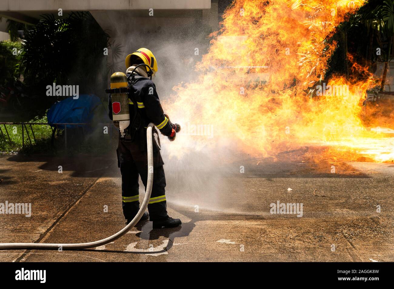 Firefighters with extinguisher spraying high pressure water to fighting ...