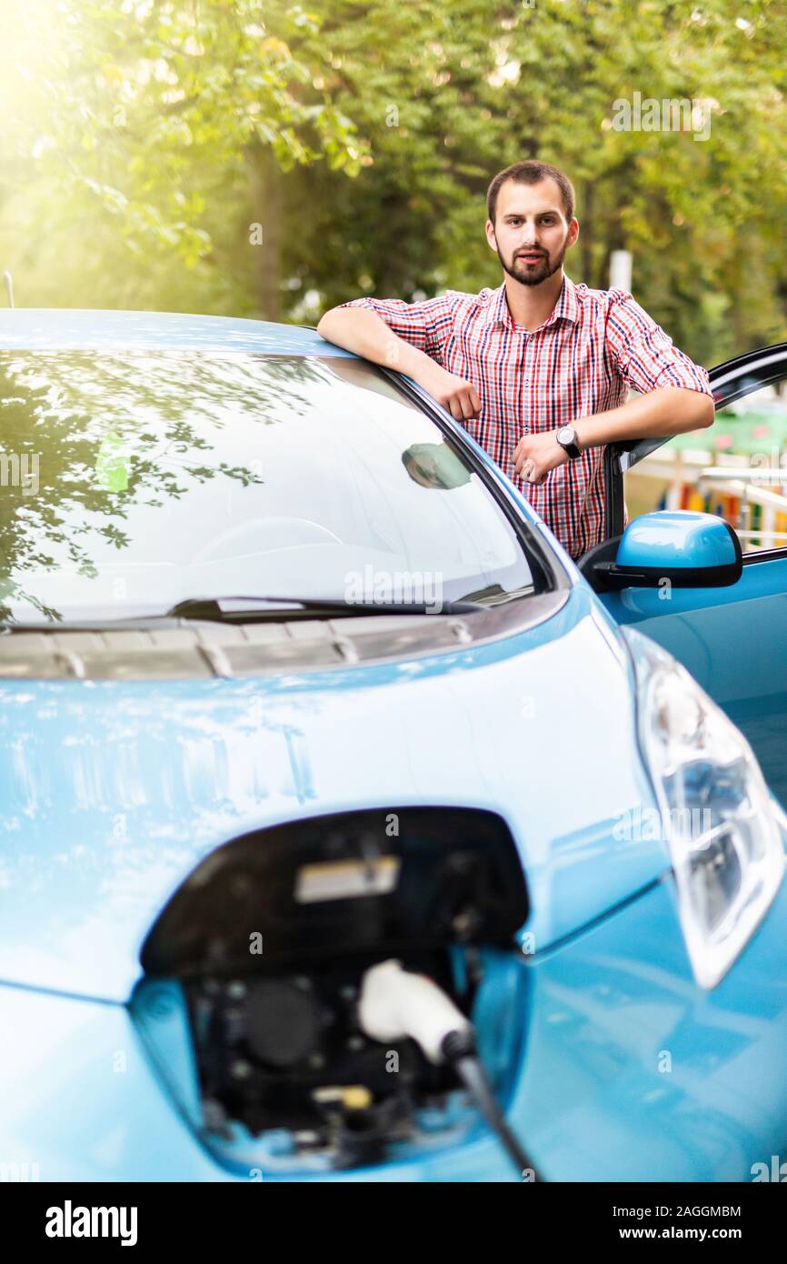 Man plugging cable to electric car Stock Photo - Alamy