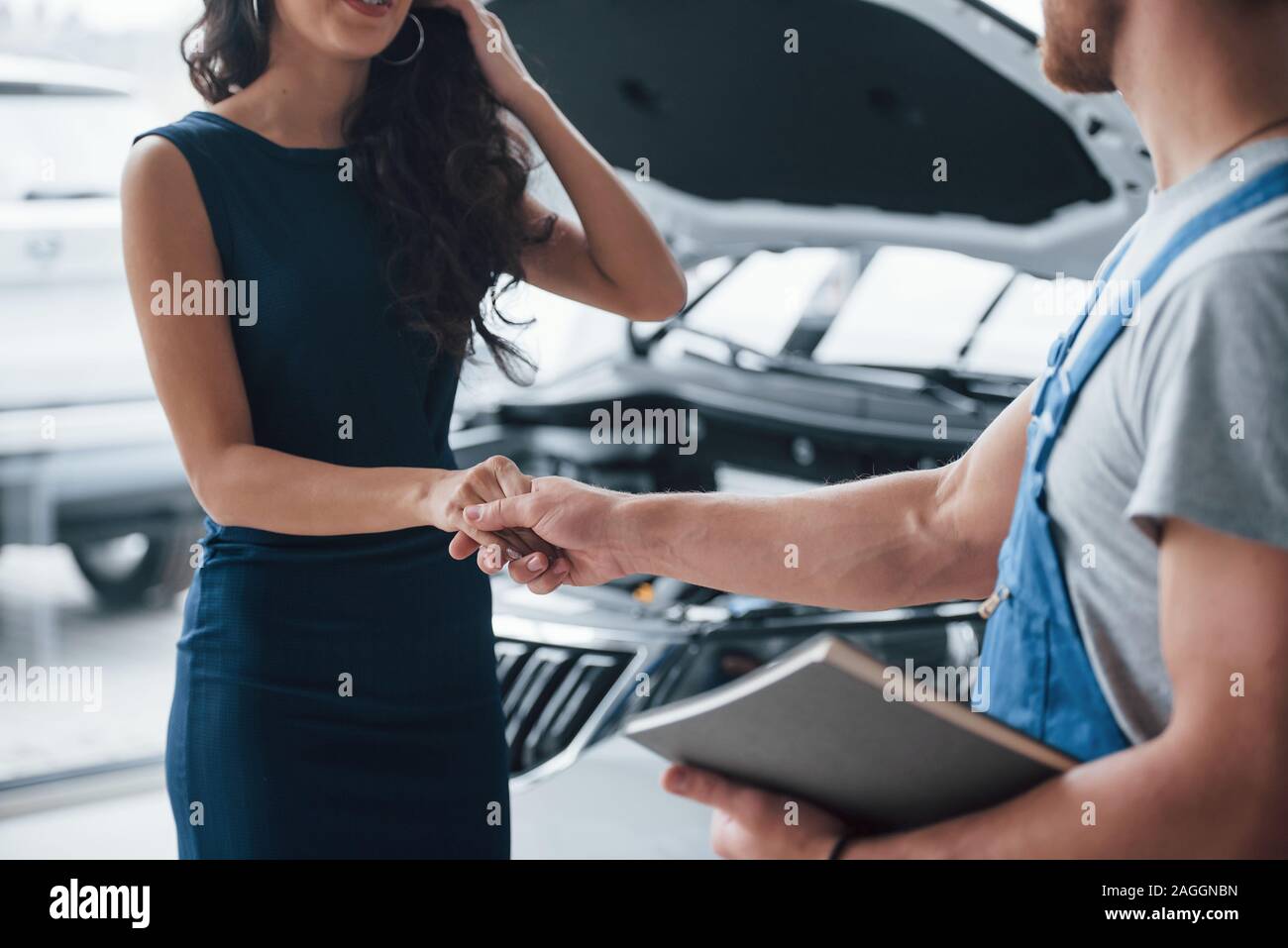 Hand shaking gesture. Woman in the auto salon with employee in blue ...