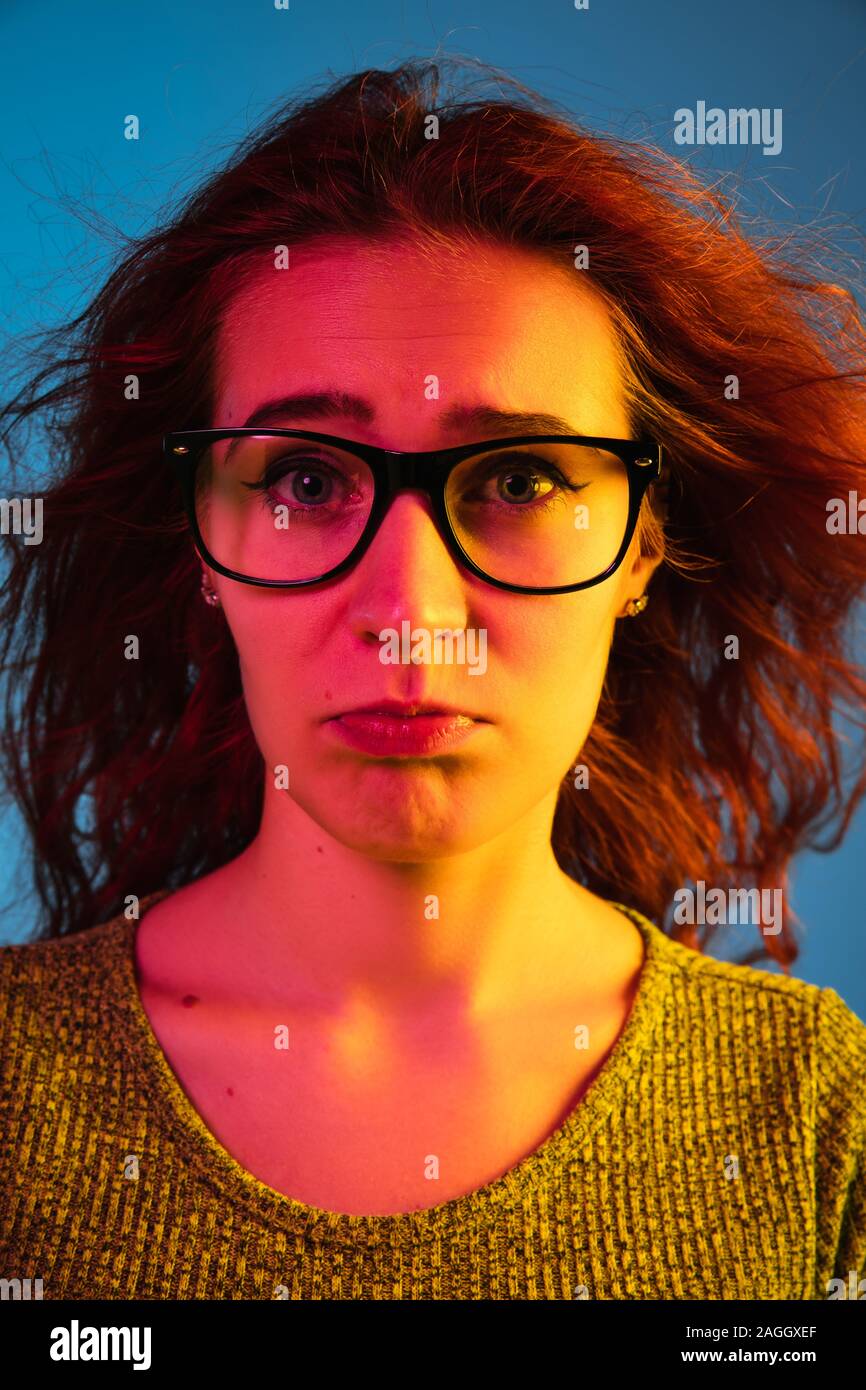 Caucasian woman's portrait isolated on blue studio background in neon ...