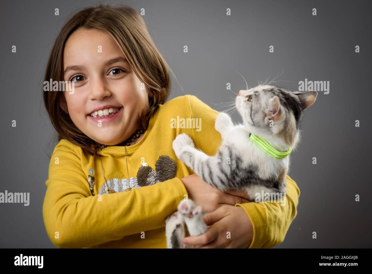 Portrait of happy young little girl with calico kitten cat. Portrait of ...