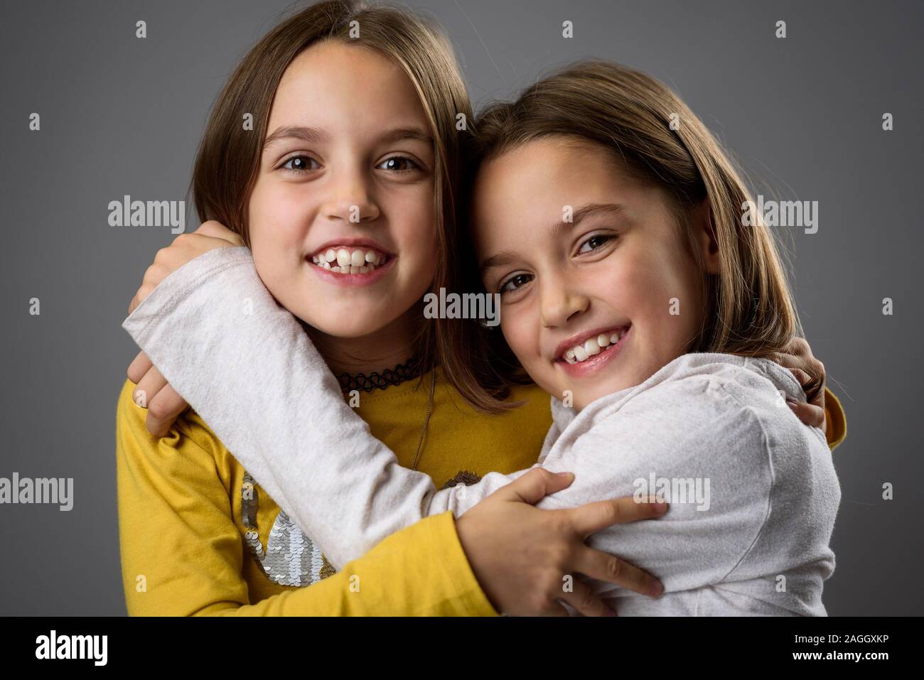 Identical twin girls sisters are posing for the camera. Happy twin ...