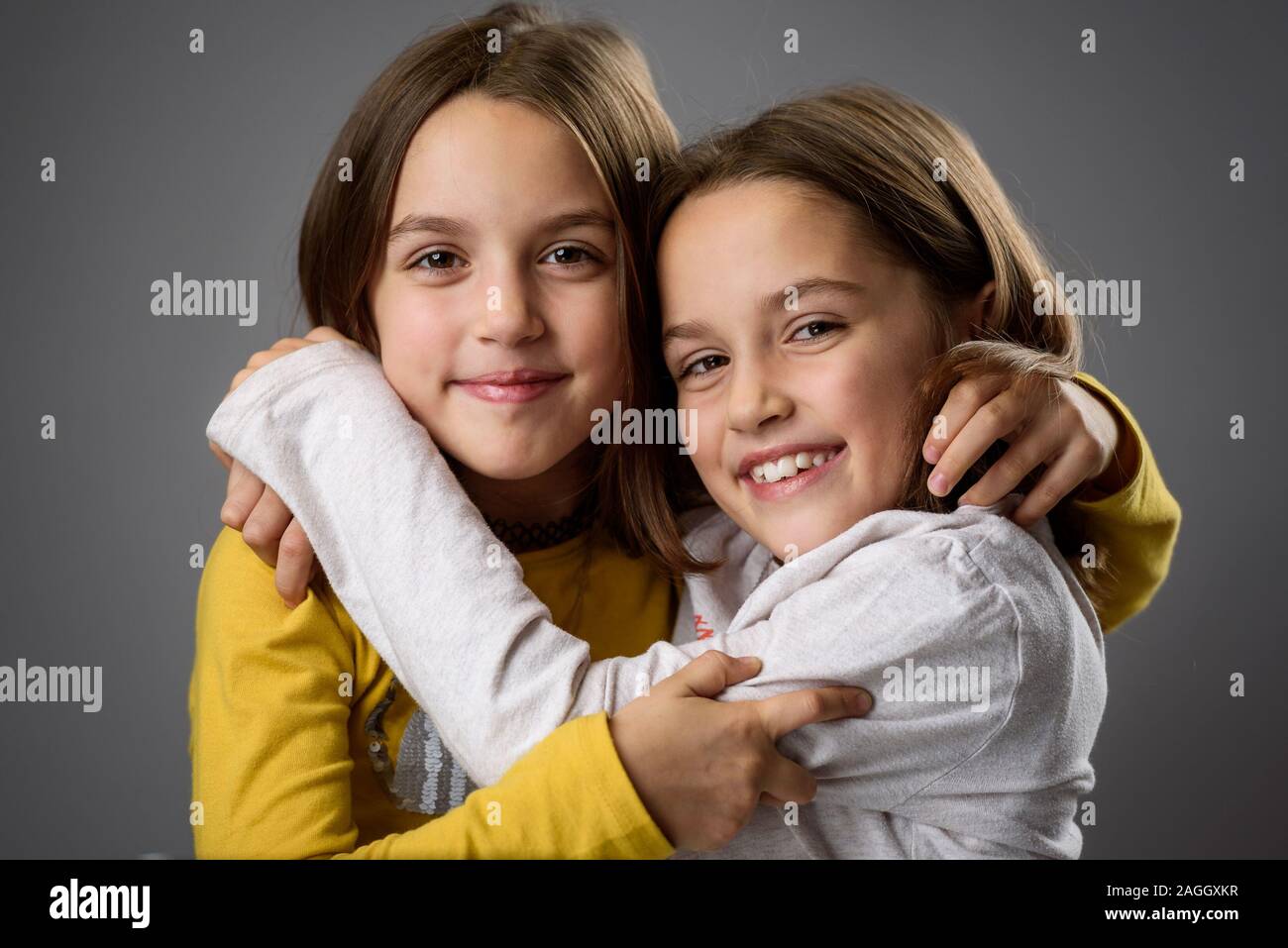 Identical twin girls sisters are posing for the camera. Happy twin ...