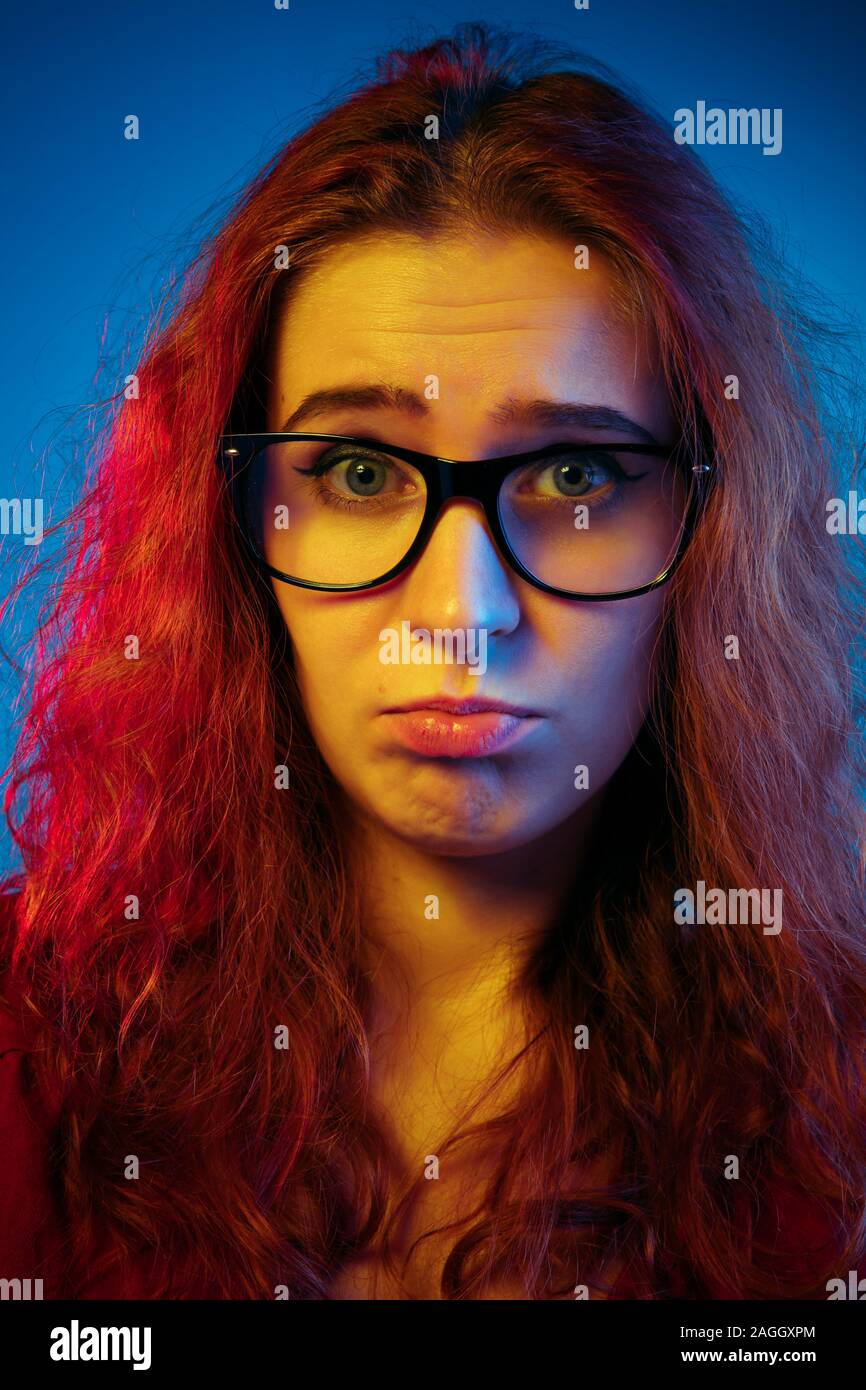 Caucasian woman's portrait isolated on blue studio background in neon ...