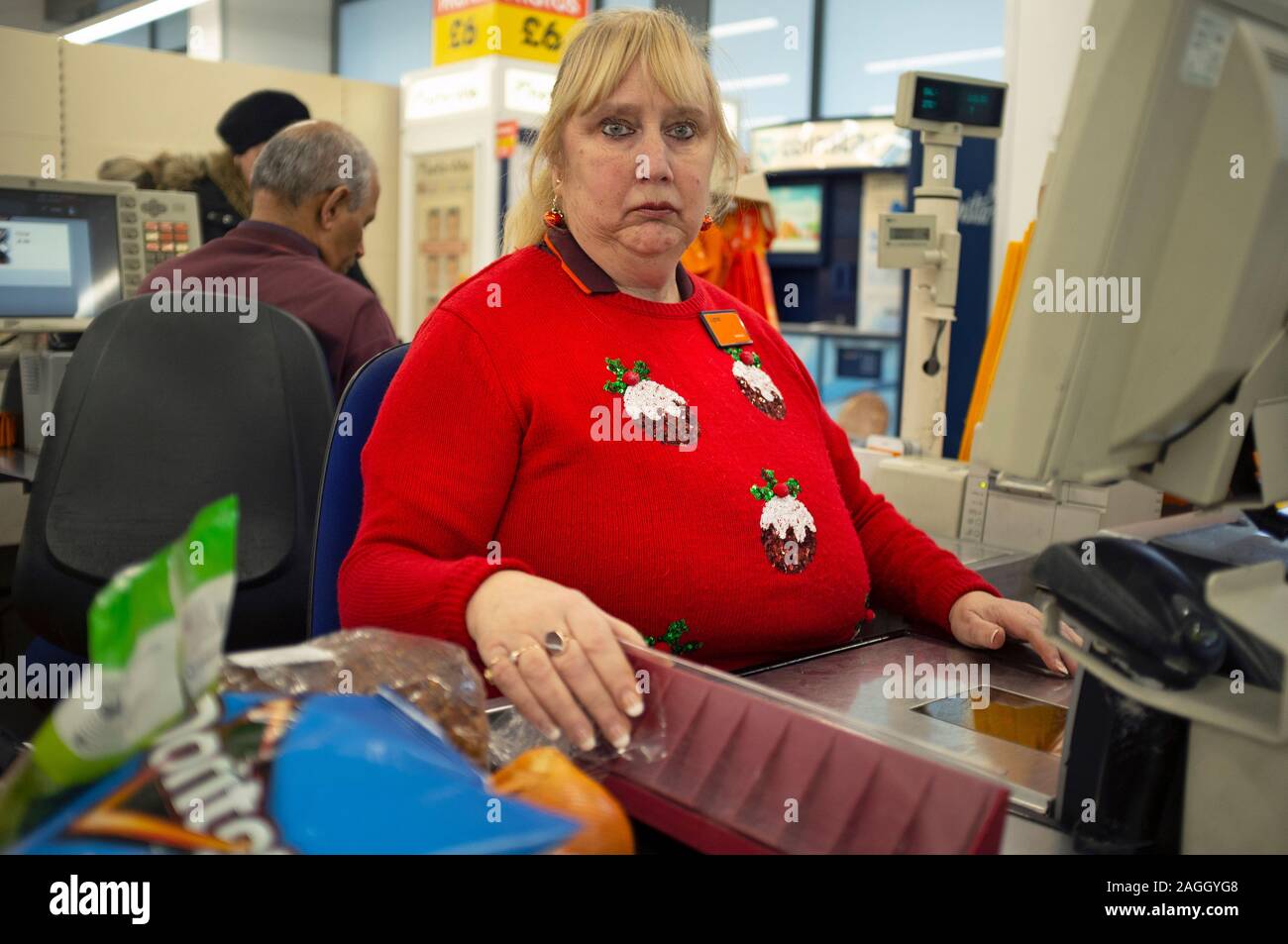At a supermarket checkout a till worker wears a Christmas jumper Stock ...