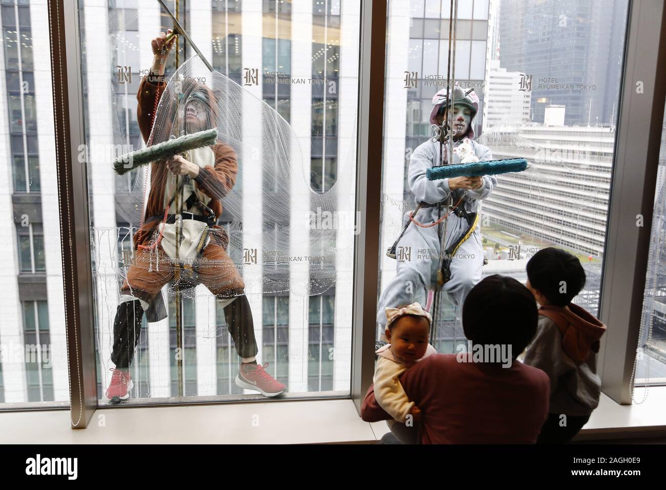 Tokyo, Japan. 19th Dec, 2019. People look at window cleaners dressed as ...