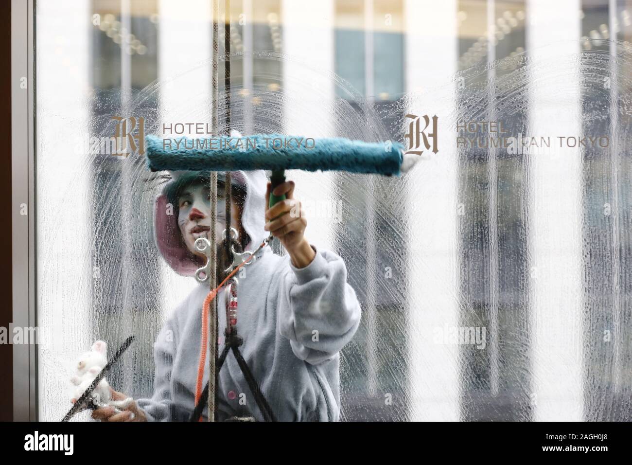 Tokyo, Japan. 19th Dec, 2019. A window cleaner dressed as a mouse wipes ...