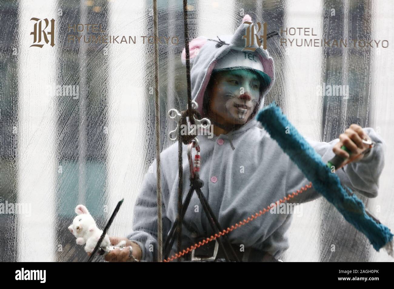 Tokyo, Japan. 19th Dec, 2019. A window cleaner dressed as a mouse wipes ...
