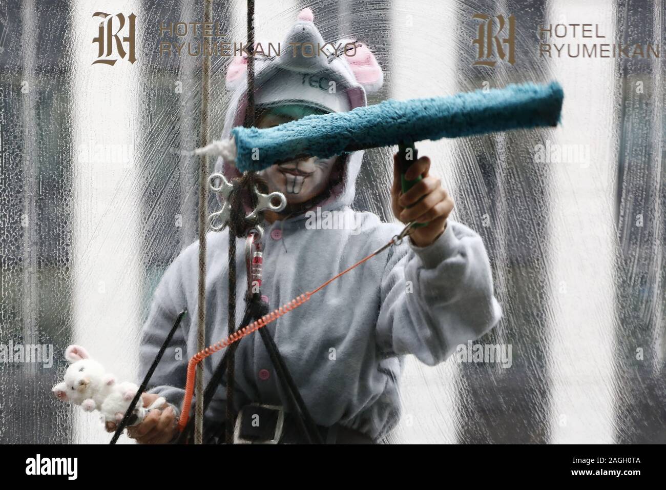 Tokyo, Japan. 19th Dec, 2019. A window cleaner dressed as a mouse wipes ...
