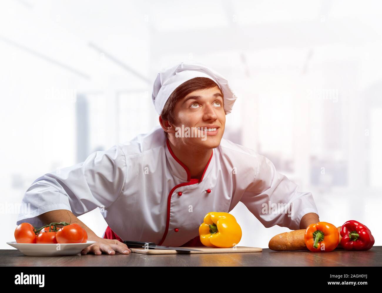 Young smiling chef standing near cooking table Stock Photo - Alamy
