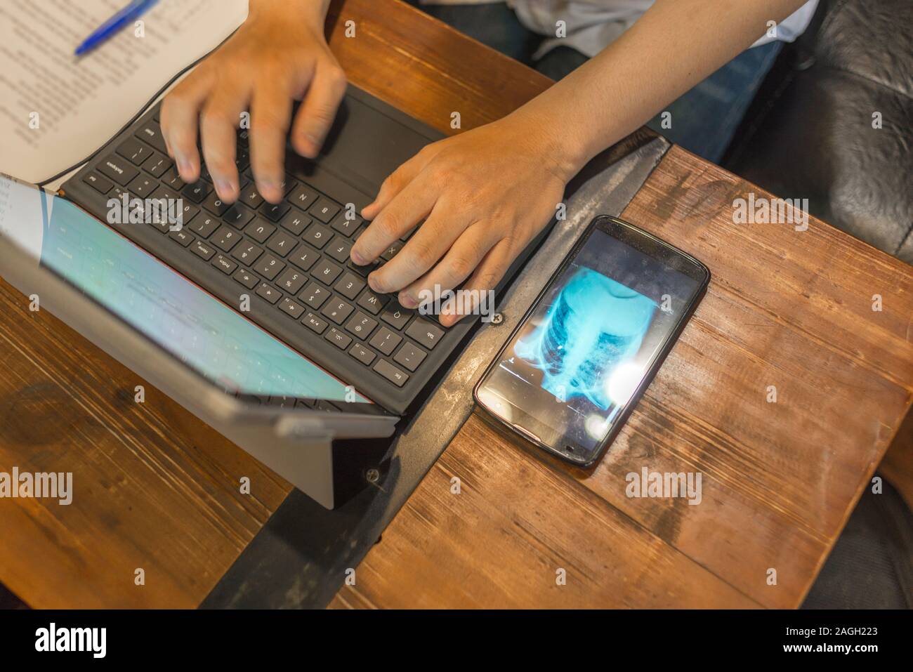 Doctor typing laptop and showing chest x-ray result on cellphone Stock ...