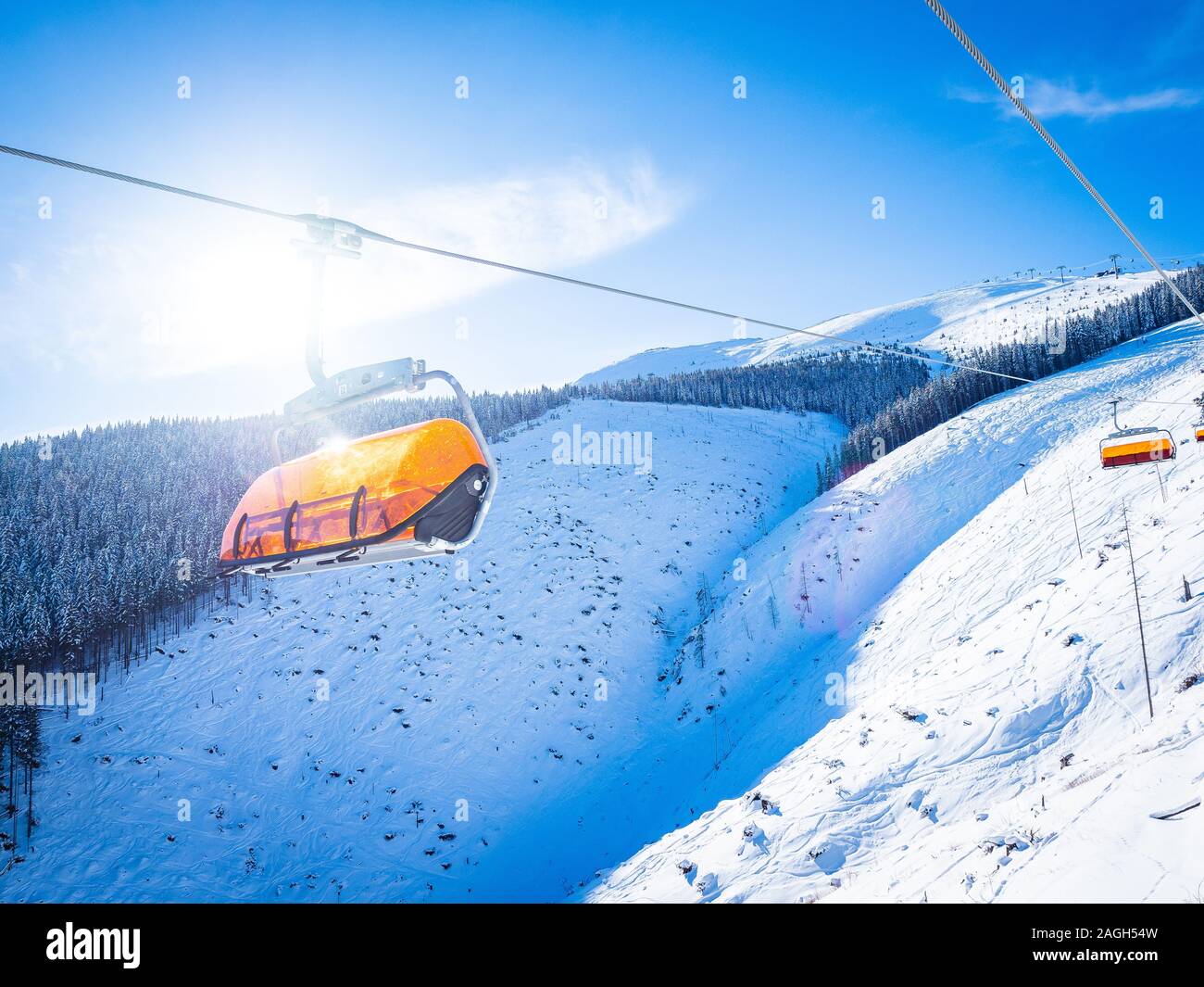 Ropeway with yellow cabins in mountains covered with the snow under a ...