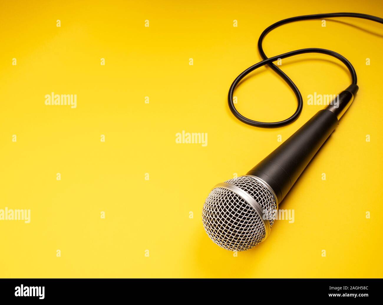 Microphone with curly cable on yellow background Stock Photo - Alamy