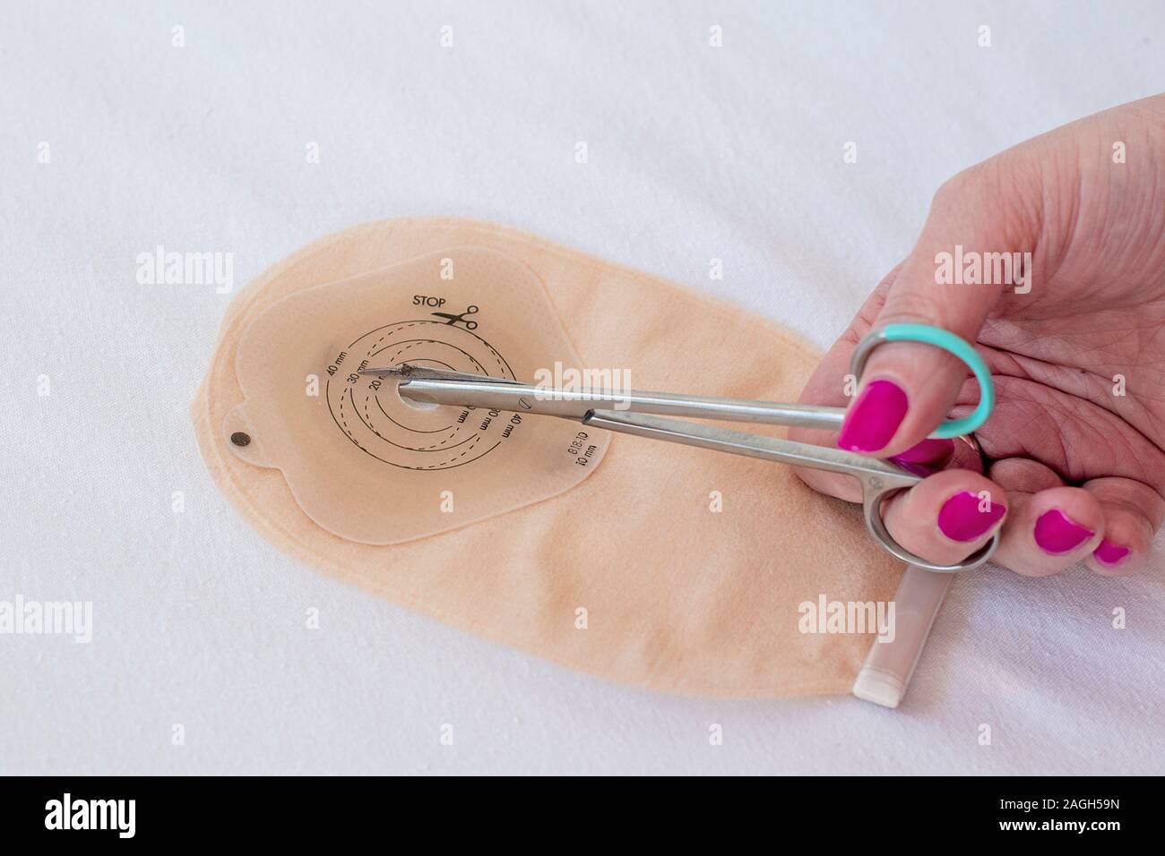 Top view on ostomy bag and scissors in female hand on white background ...