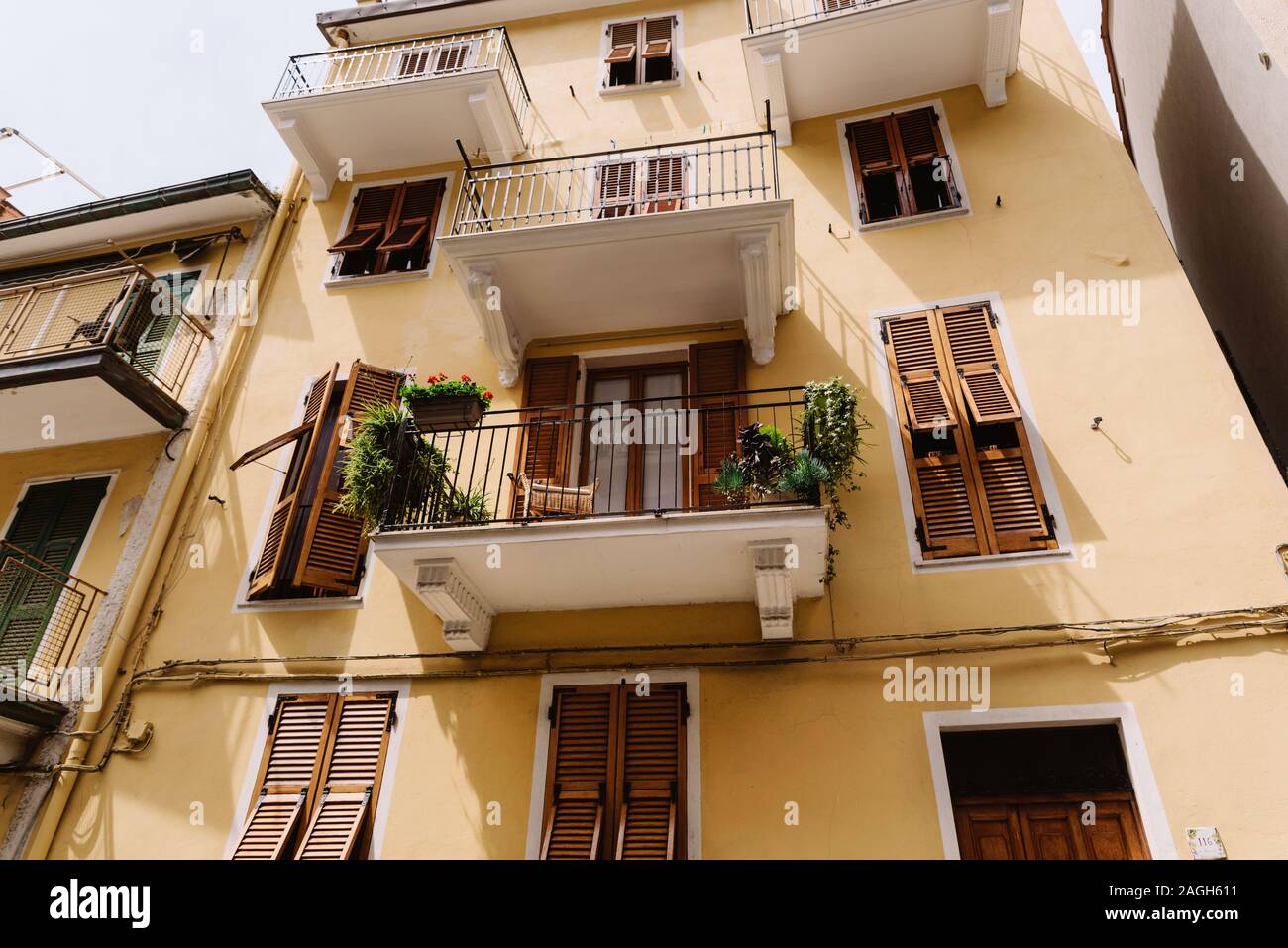Large yellow Italian house with colourful Windows and vases. Stylish ...