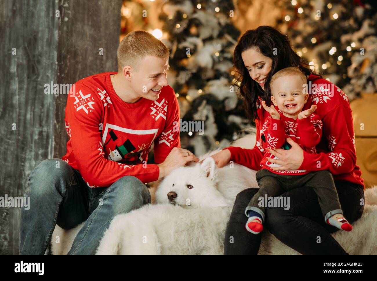 Family with little son sits next to white samoyed dog and has a fun ...