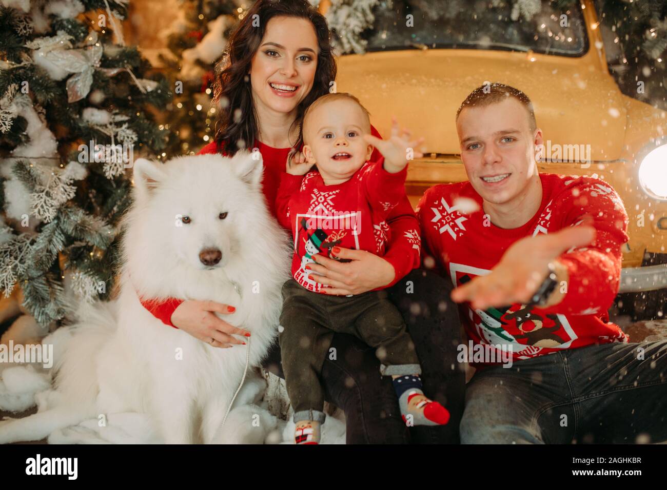 Happy family with little son sits next to white samoyed dog against ...