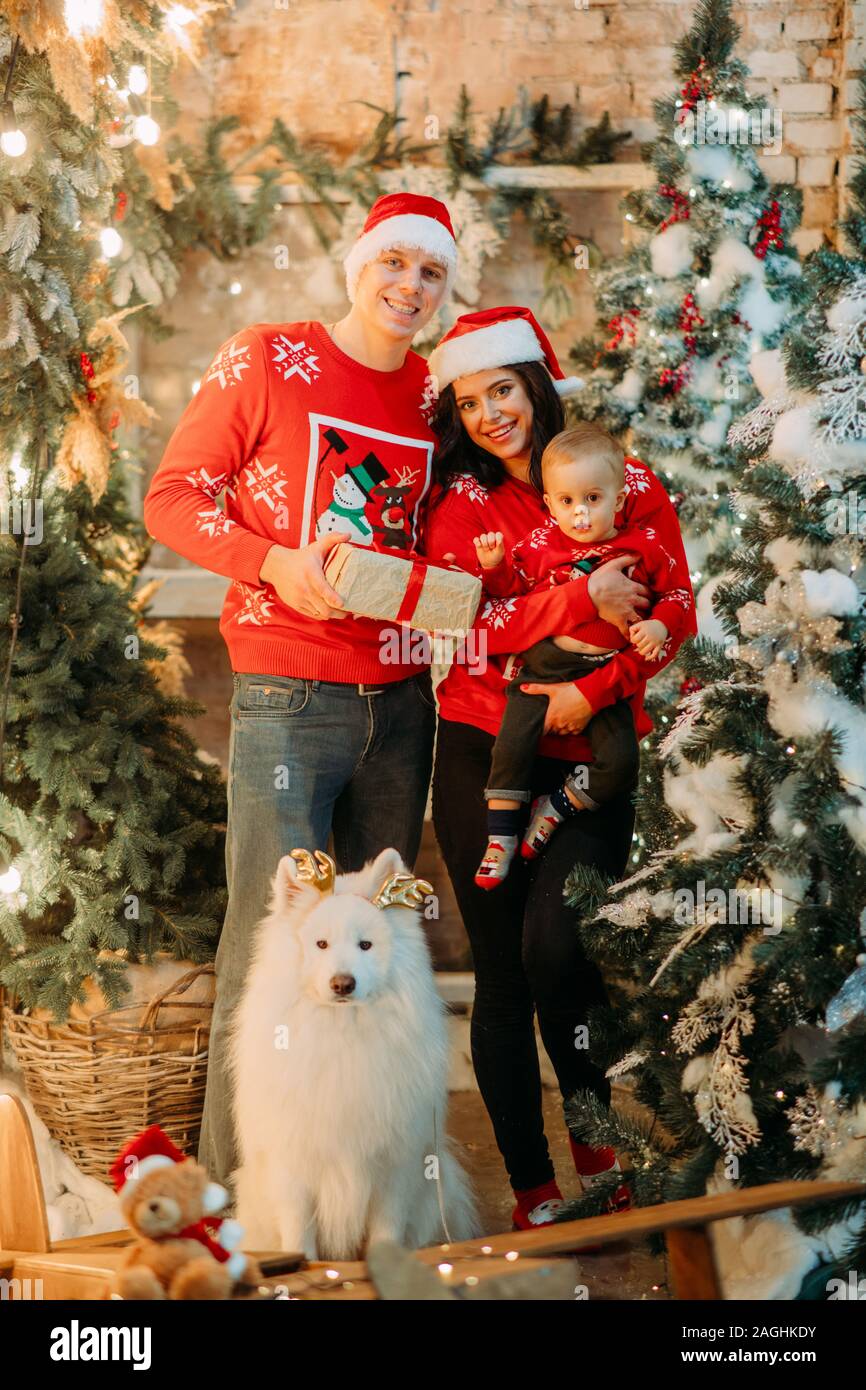 Happy family poses next to white samoyed dog against background of ...