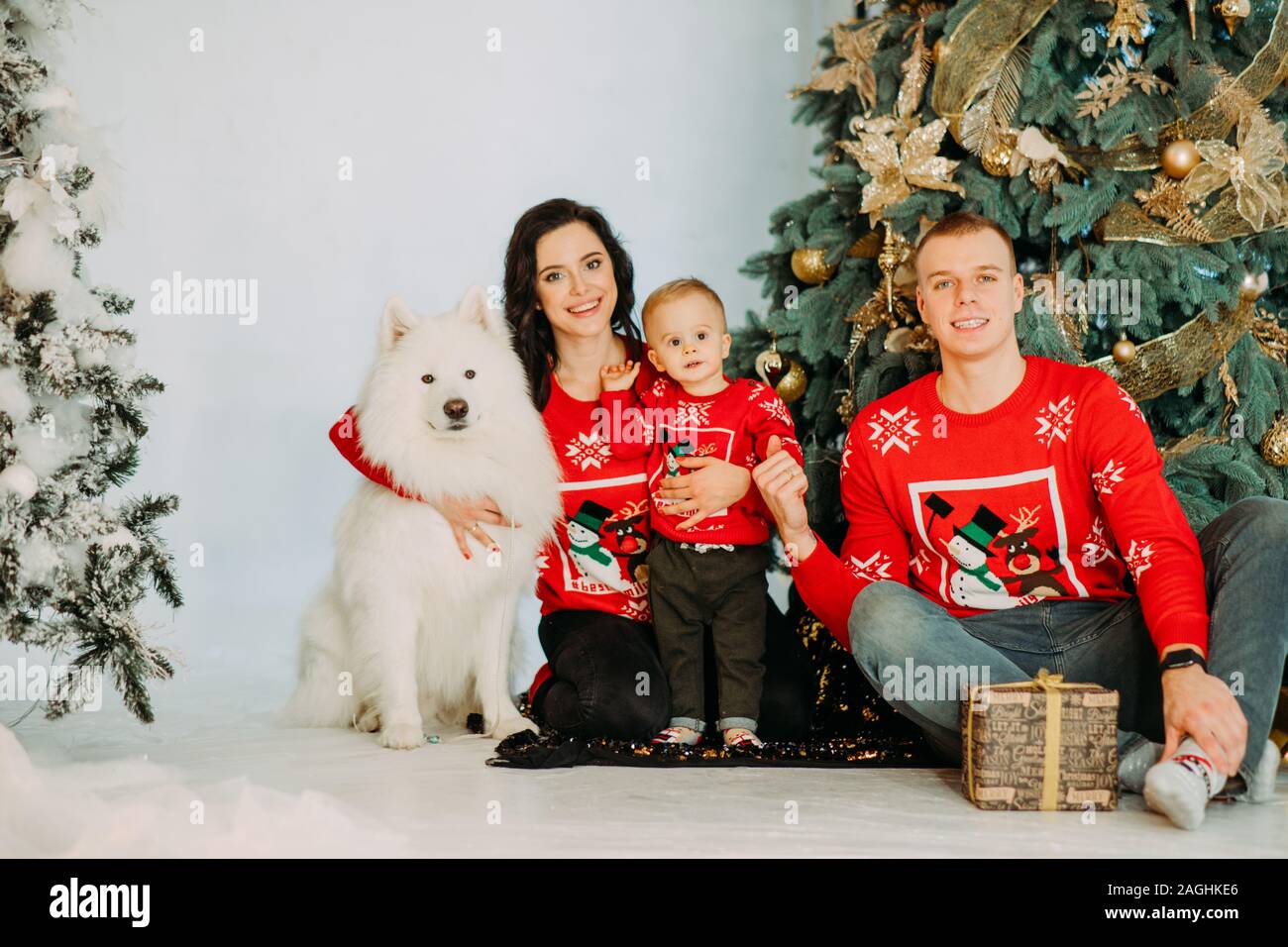 Happy family poses next to white samoyed dog against background of ...