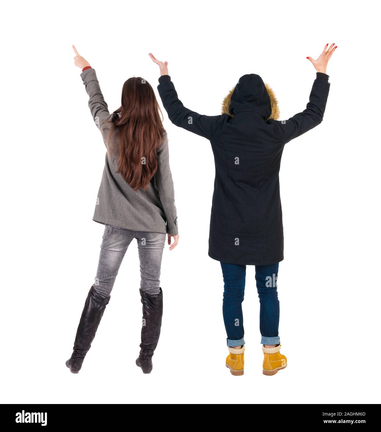 Back view of two pointing young girl in winter jacket. Rear view people ...