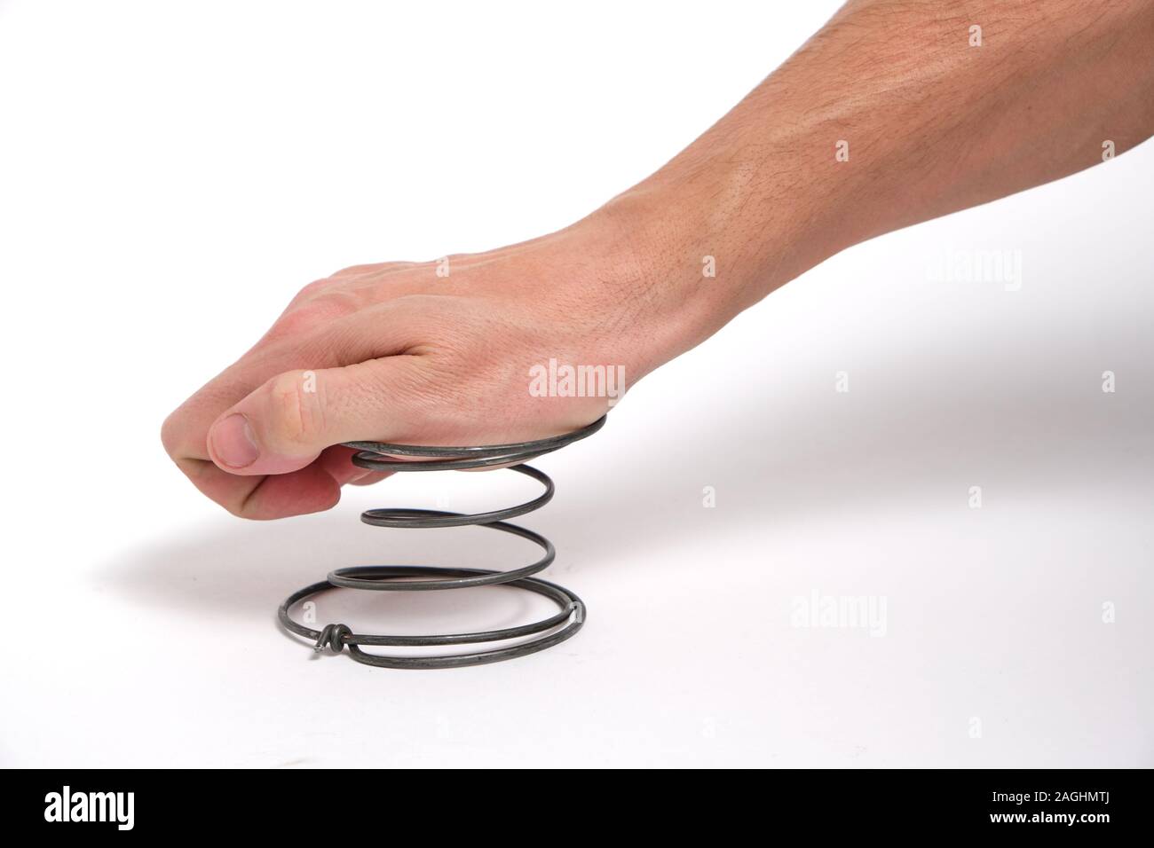 A man's hand presses on a spring, on a white background.Exert pressure ...