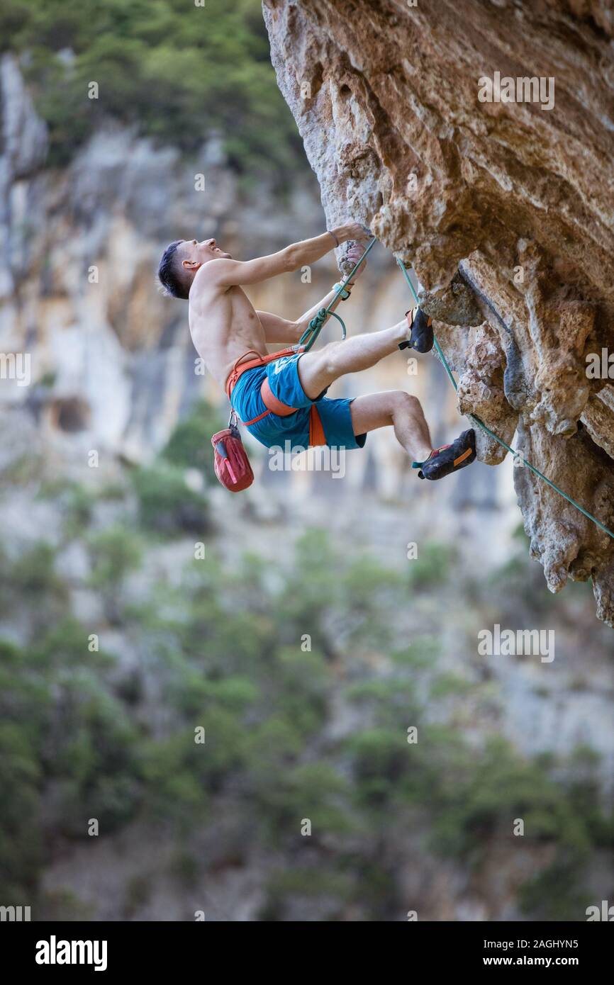 Young man looking up while climbing challenging route on overhanging ...