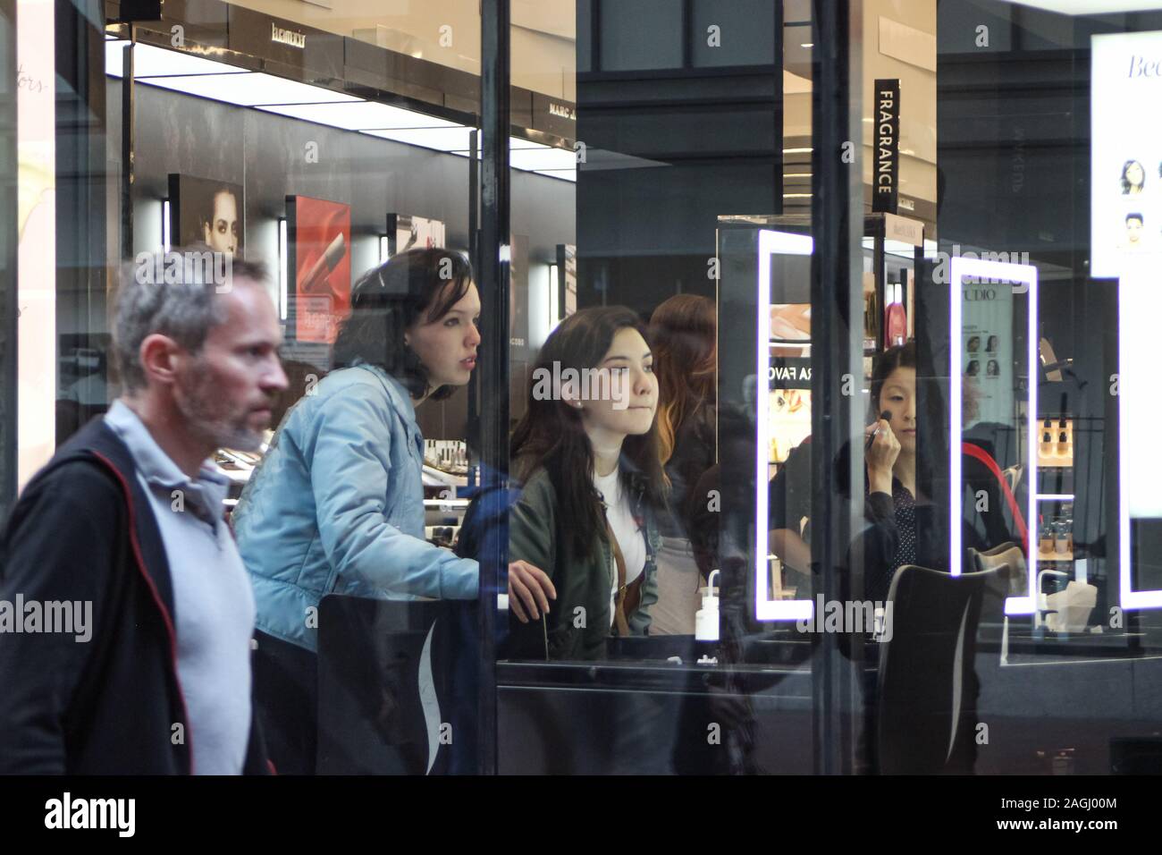 Young women or teenage girls at beauty store viewed through shop window ...