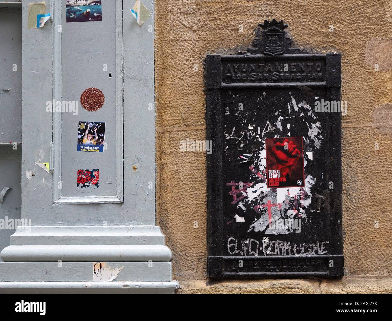 graffiti and stickers on grey painted column and black civic notice ...