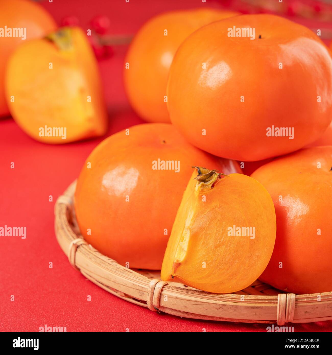 Fresh beautiful sliced sweet persimmon kaki isolated on red table ...