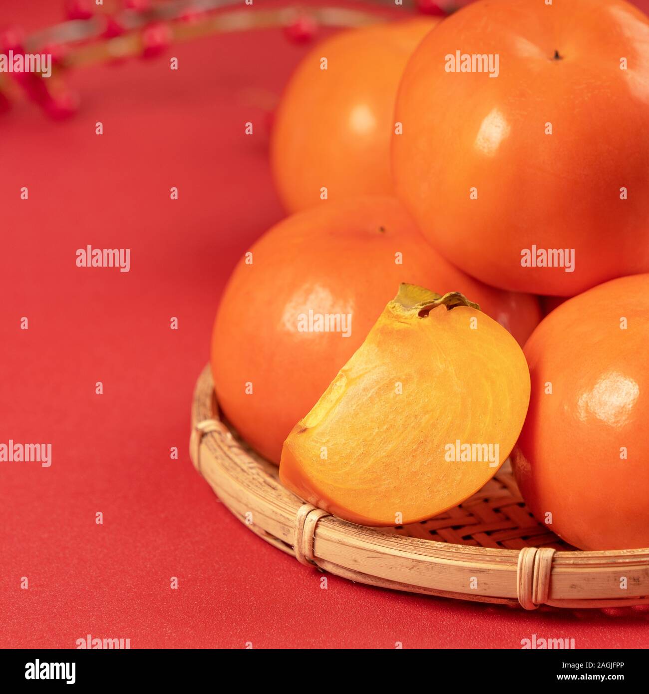 Fresh beautiful sliced sweet persimmon kaki isolated on red table ...