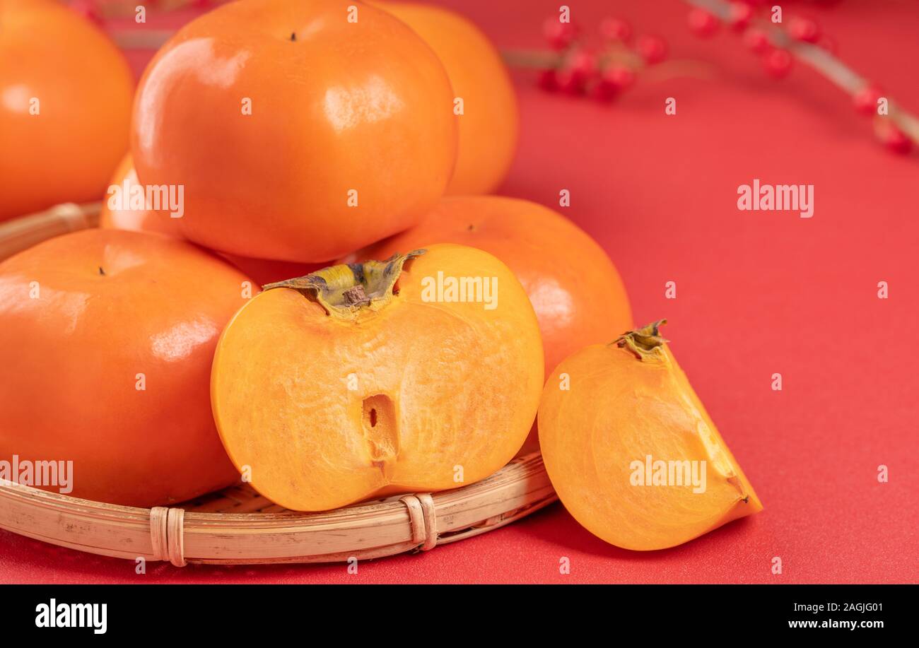 Fresh beautiful sliced sweet persimmon kaki isolated on red table ...