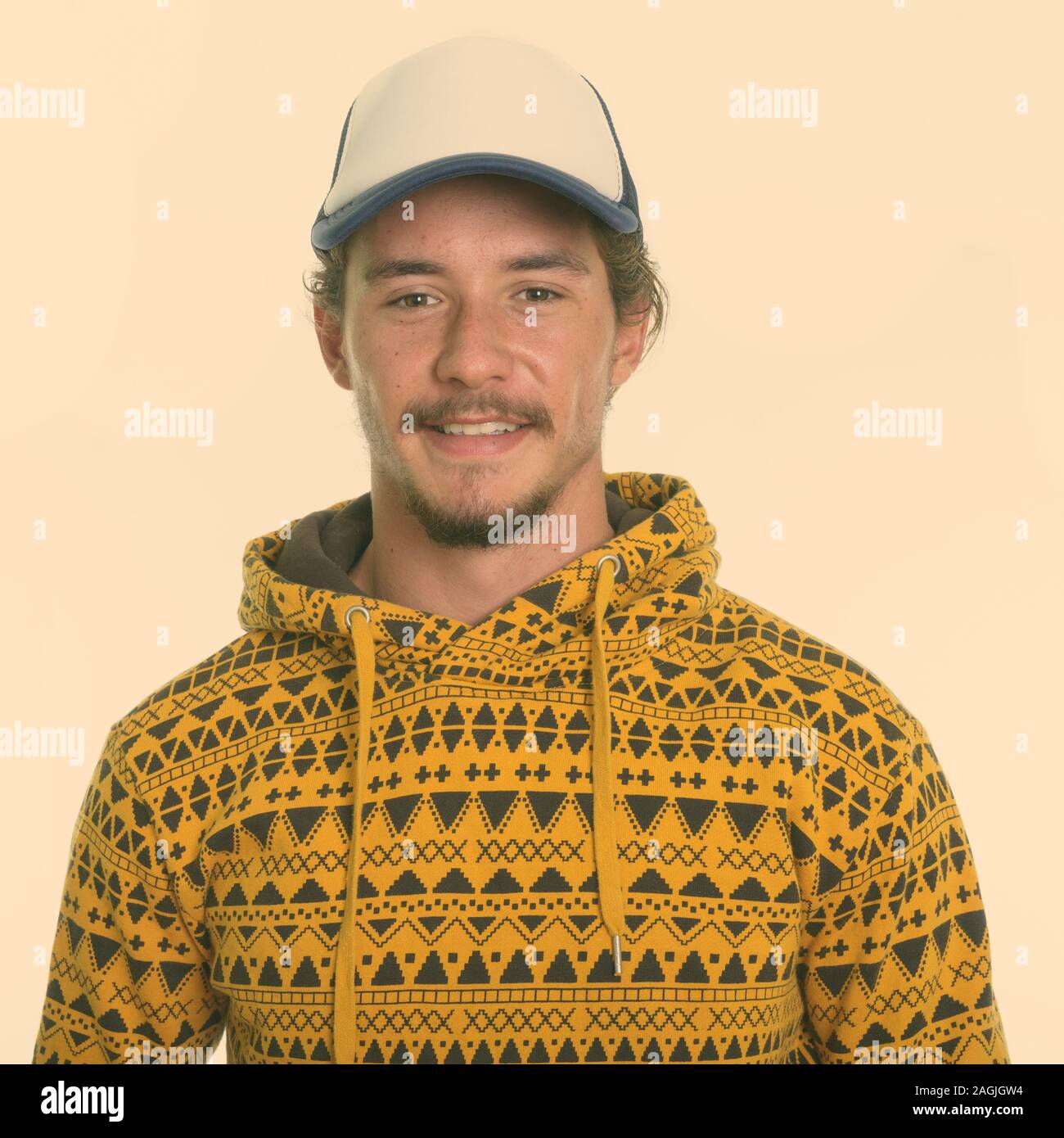 Studio shot of young happy man smiling while wearing cap isolated ...