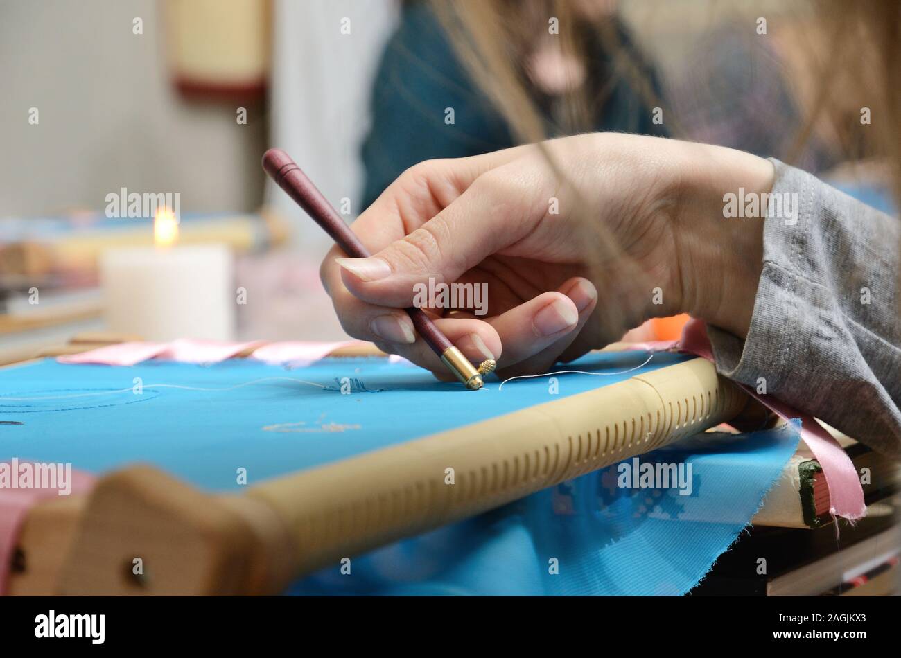 Human hand with a hook on the embroidery frame with fabric attached ...