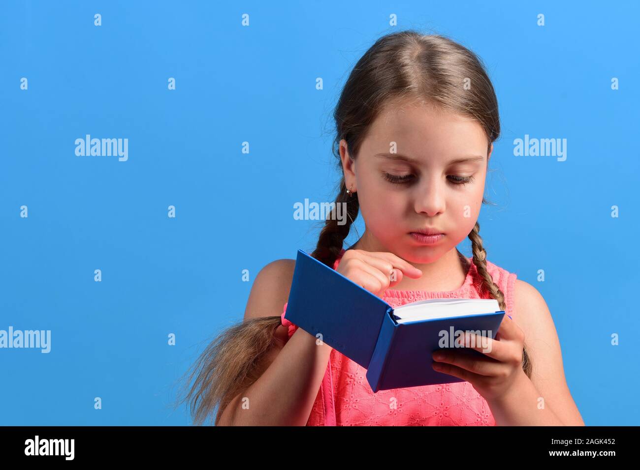 Girl reads blue book. School girl with concentrated face isolated on ...