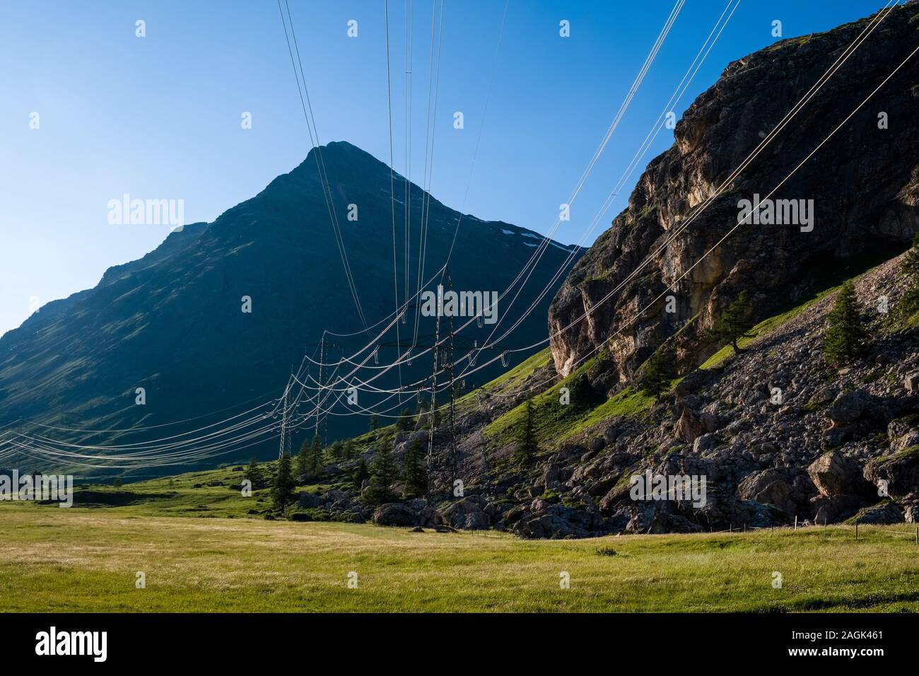 Power lines leading up an agricultural used valley, a big dark mountain ...