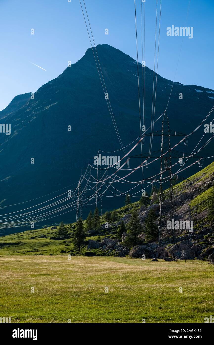 Power lines leading up an agricultural used valley, a big dark mountain ...