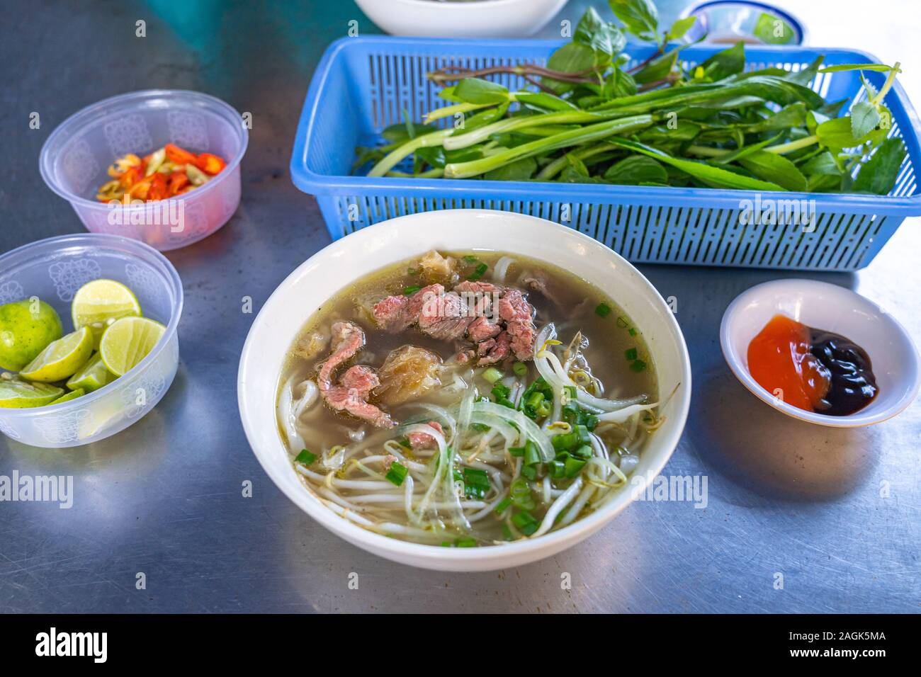 Vietnamese local food- Pho beef noodles soup served with vegetables ...