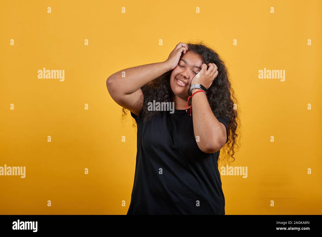 Attractive afro-american overweight woman keeping hand on head, smiling ...