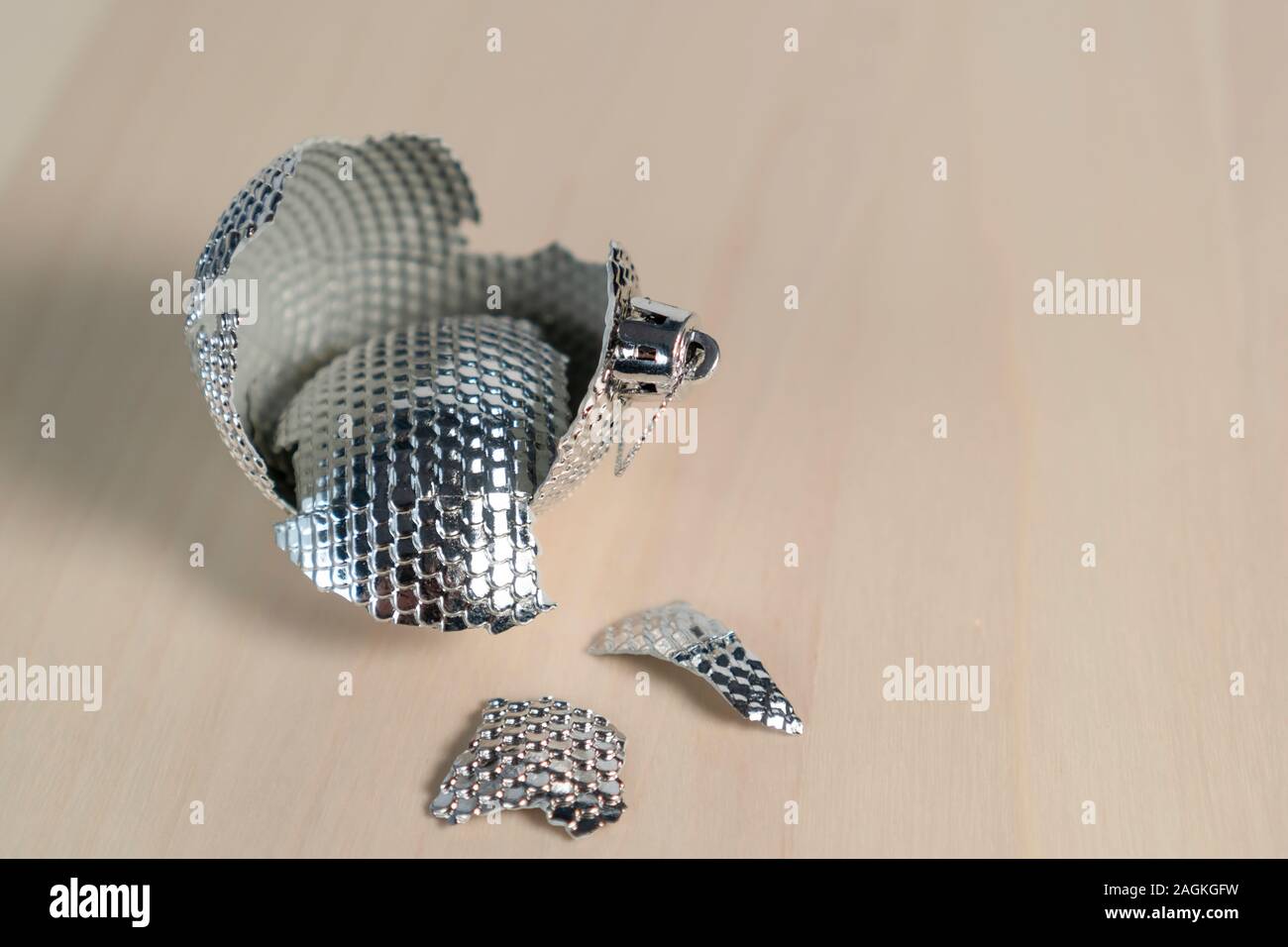 Broken shiny gray christmas ball with cracks and splinters on a wooden ...