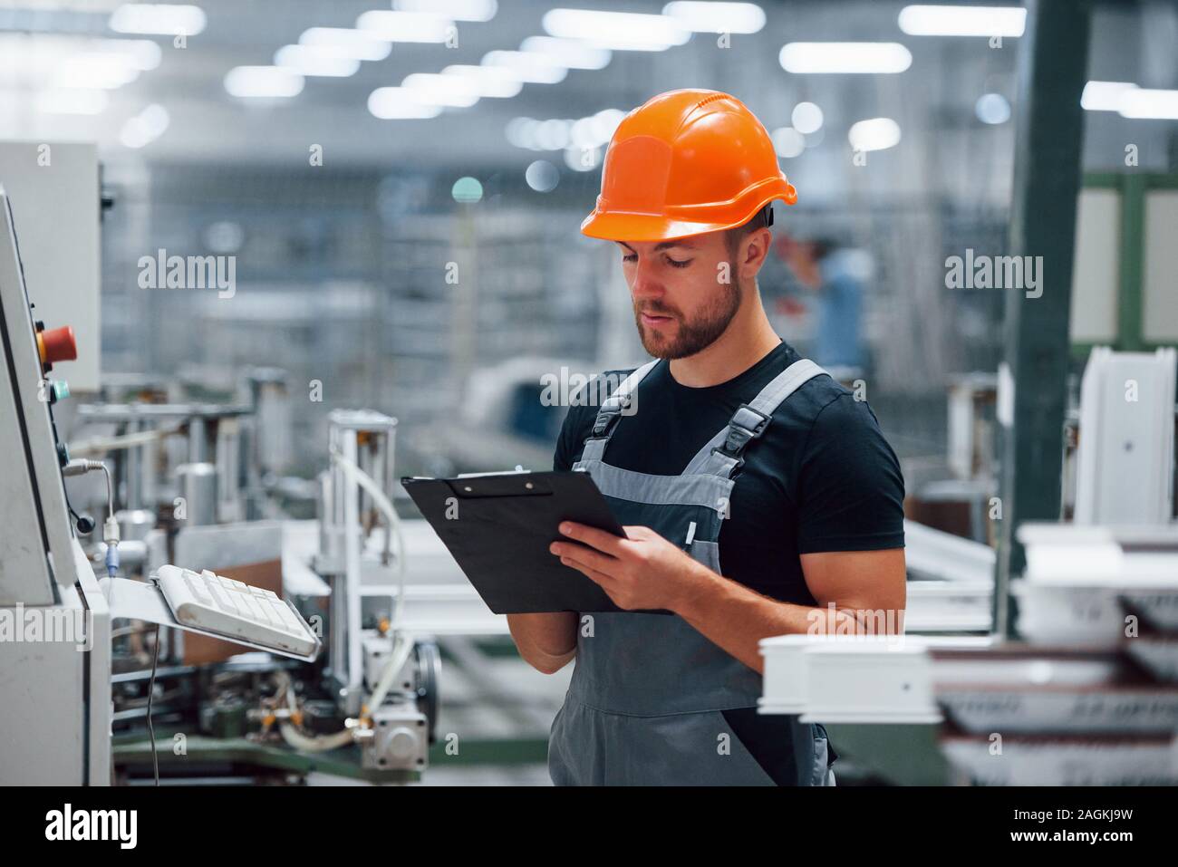 Looks at equipment and makes notes. Industrial worker indoors in ...