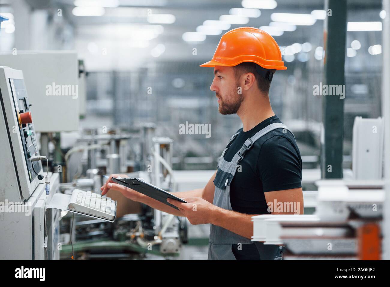 Looks at equipment and makes notes. Industrial worker indoors in ...
