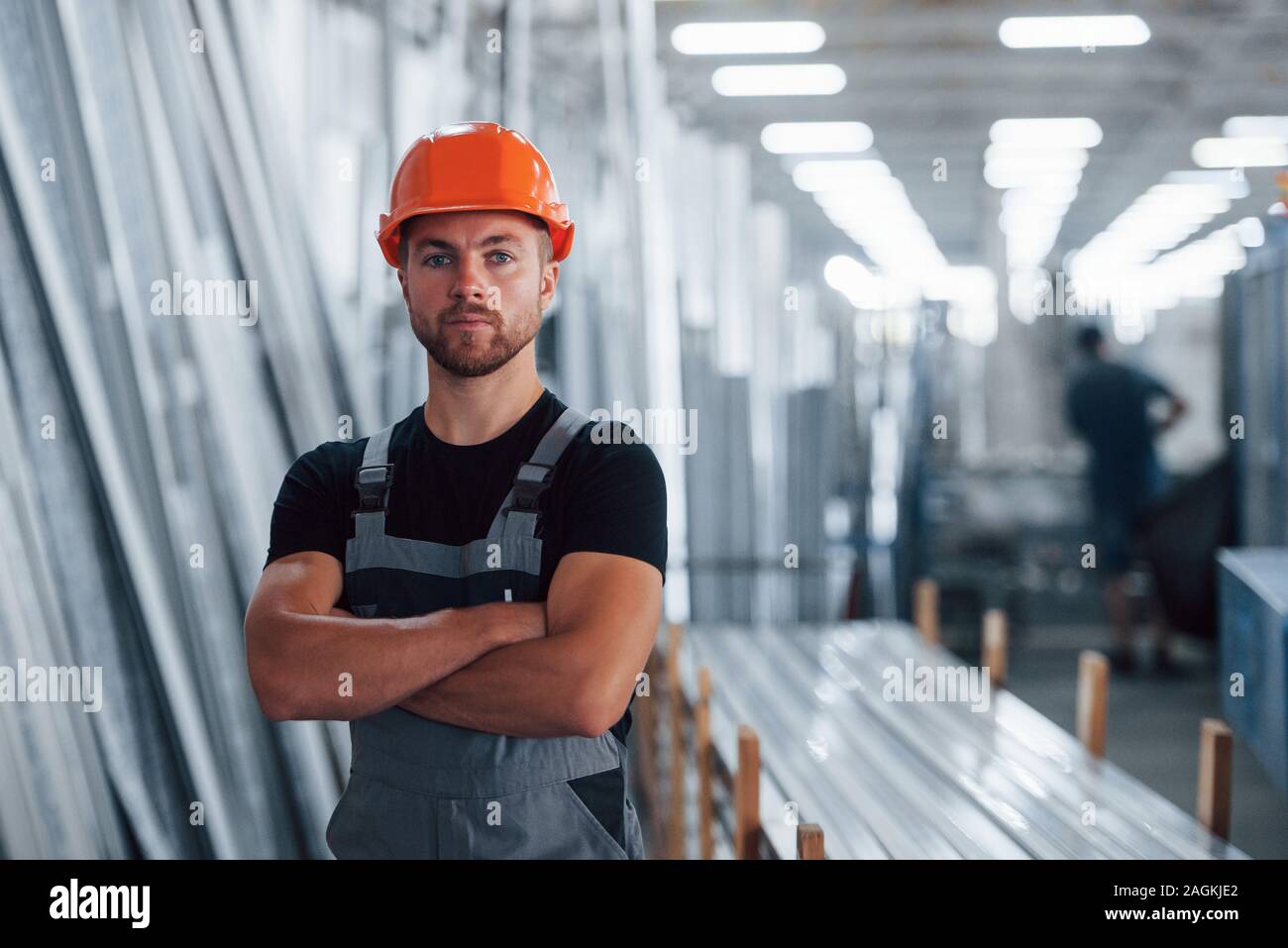 Stands with arms crossed. Portrait of male industrial worker indoors in ...