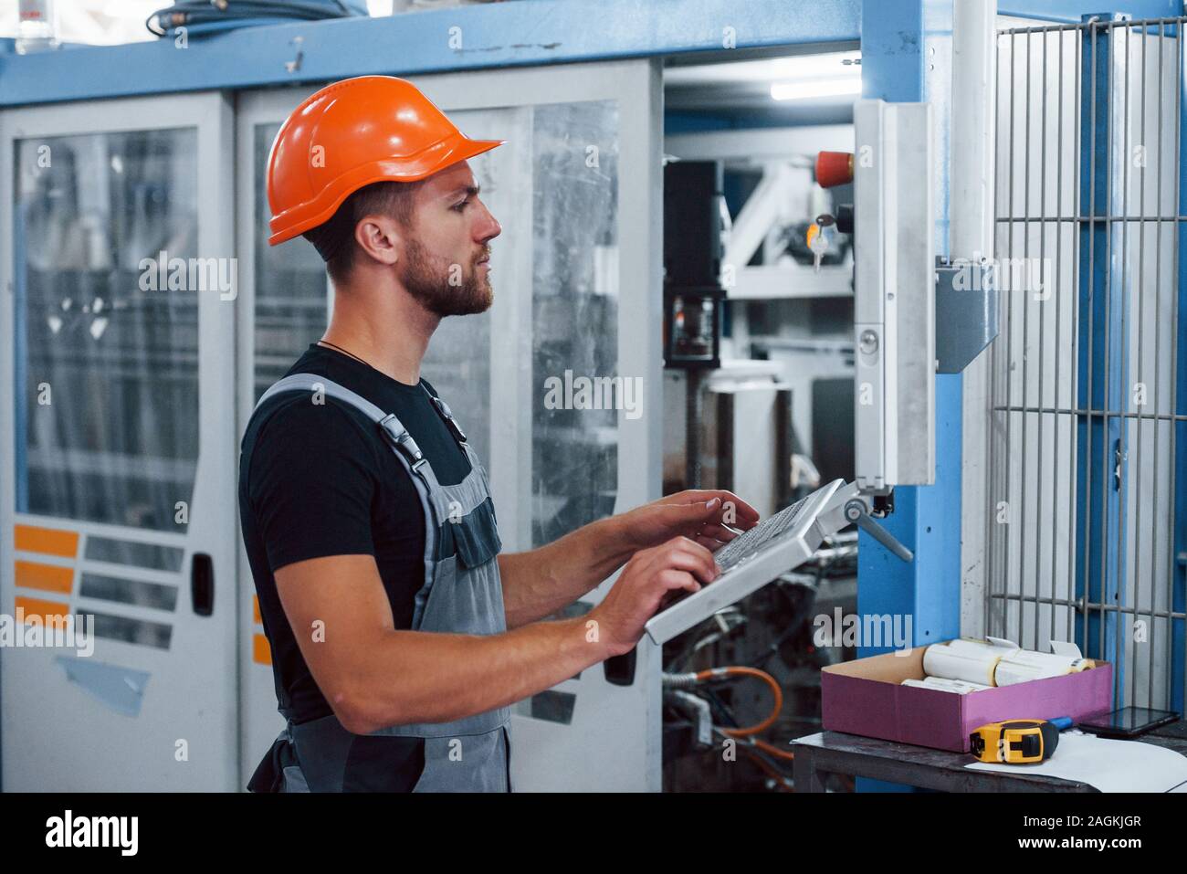 Using machine to program operations. Industrial worker indoors in ...